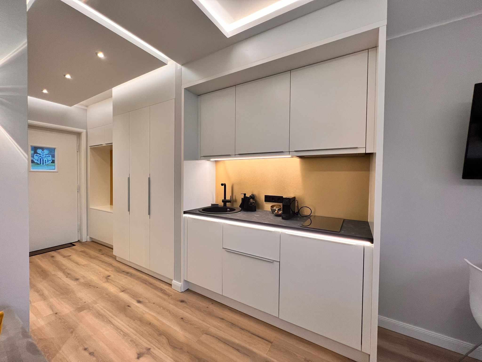 Uma cozinha moderna com armários embutidos, bancada e iluminação sob os armários.