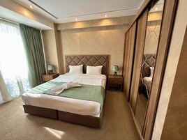 Quarto de hotel com uma cama grande, um guarda-roupa e uma janela com cortinas.