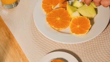 Prato de café da manhã com fatias de laranja e uma faca, um copo de suco de laranja e um prato menor com uma fatia de laranja.