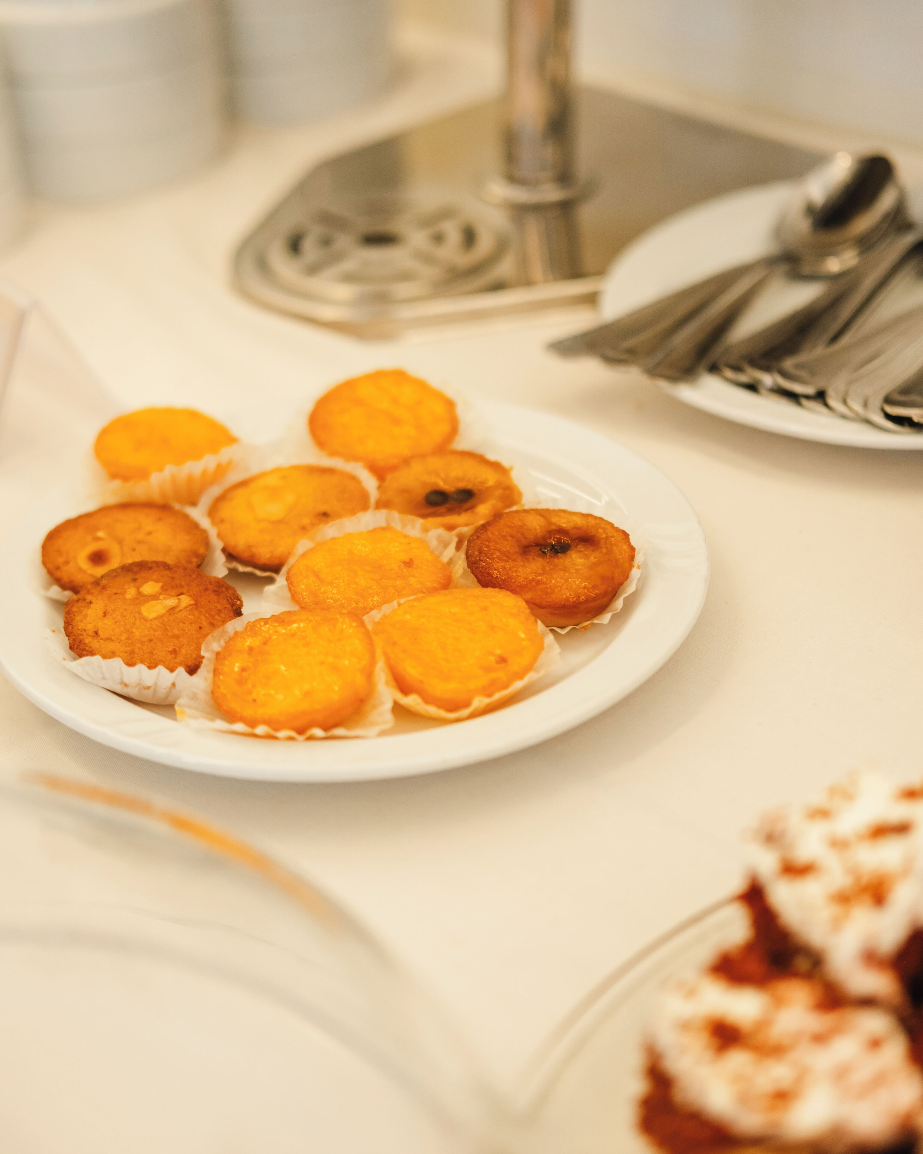 Um prato branco com vários doces redondos sobre uma mesa branca.