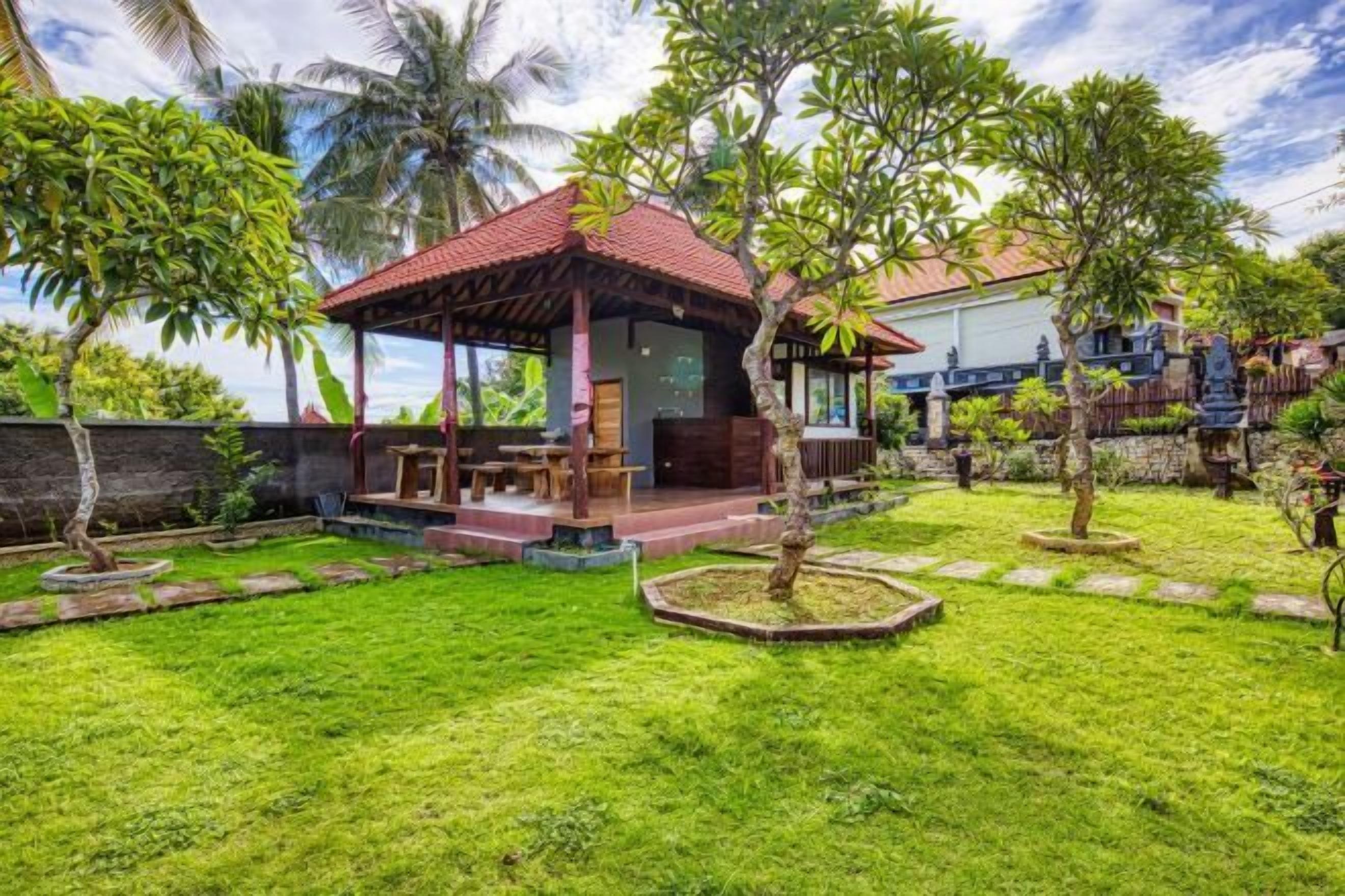 Um jardim exuberante com um gazebo, palmeiras e um muro de pedra.