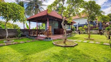 Um jardim exuberante com um gazebo, palmeiras e um muro de pedra.