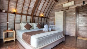 Quarto com teto de madeira, cama com almofadas, mesa de cabeceira e guarda-roupa.