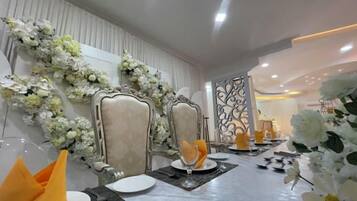 Uma área de refeições com uma mesa comprida, cadeiras e decorações florais.