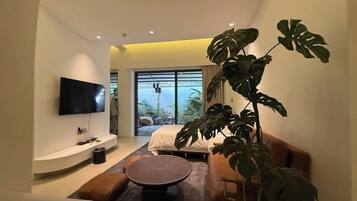 Uma sala de estar moderna com uma televisão de tela plana, um sofá, uma mesa de centro e uma planta grande.