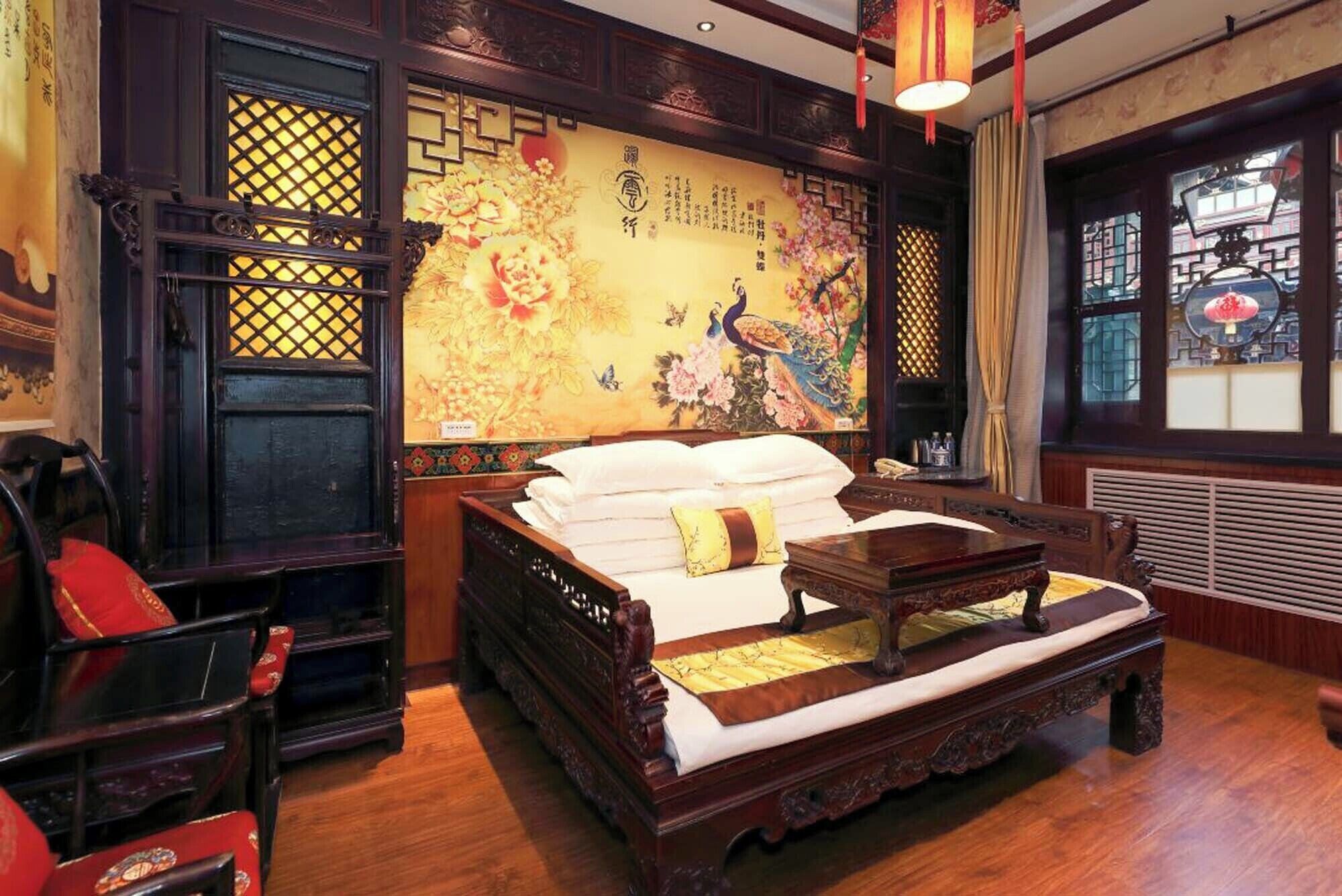 Quarto tradicional com cama de madeira, uma cadeira vermelha e parede com desenhos detalhados.