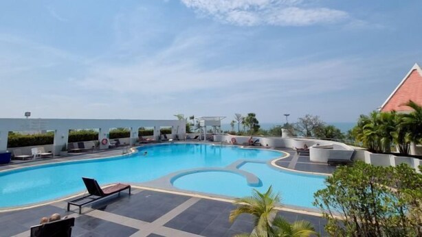 Piscina com espreguiçadeiras e vista para o oceano.