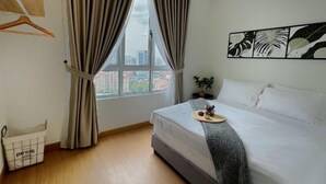 Quarto com cama, cortinas, janela, planta e obra de arte na parede.
