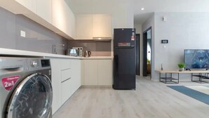 Uma cozinha moderna com máquina de lavar, refrigerador e televisão de tela plana em um suporte.