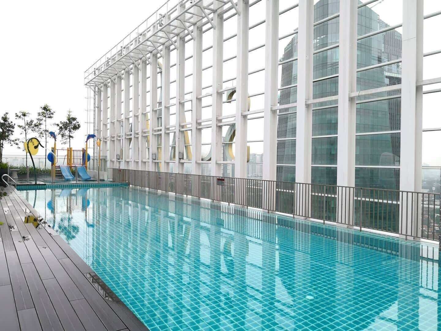 Piscina com deck ladrilhado e área de recreação.