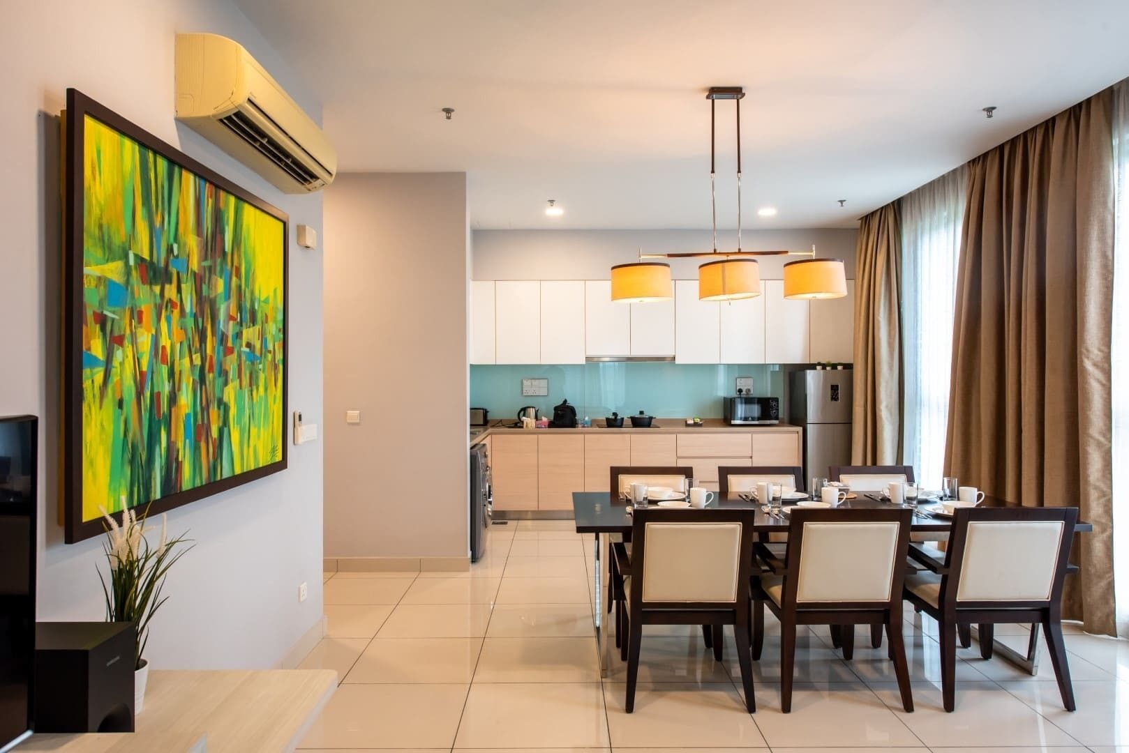 Cozinha moderna com armários brancos, área de jantar com mesa e cadeiras, e um grande quadro abstrato na parede.