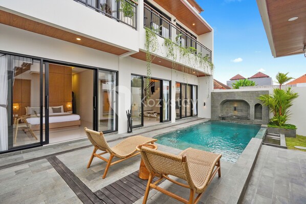 Uma casa moderna de dois andares com piscina, grandes janelas e área de estar externa.