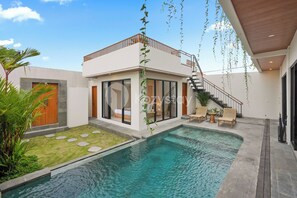 Uma casa moderna com piscina, varanda e escadaria que leva a um segundo andar.
