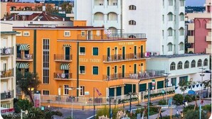 Um edifício de vários andares com varandas e uma placa com a inscrição 'Villa Tadini'.