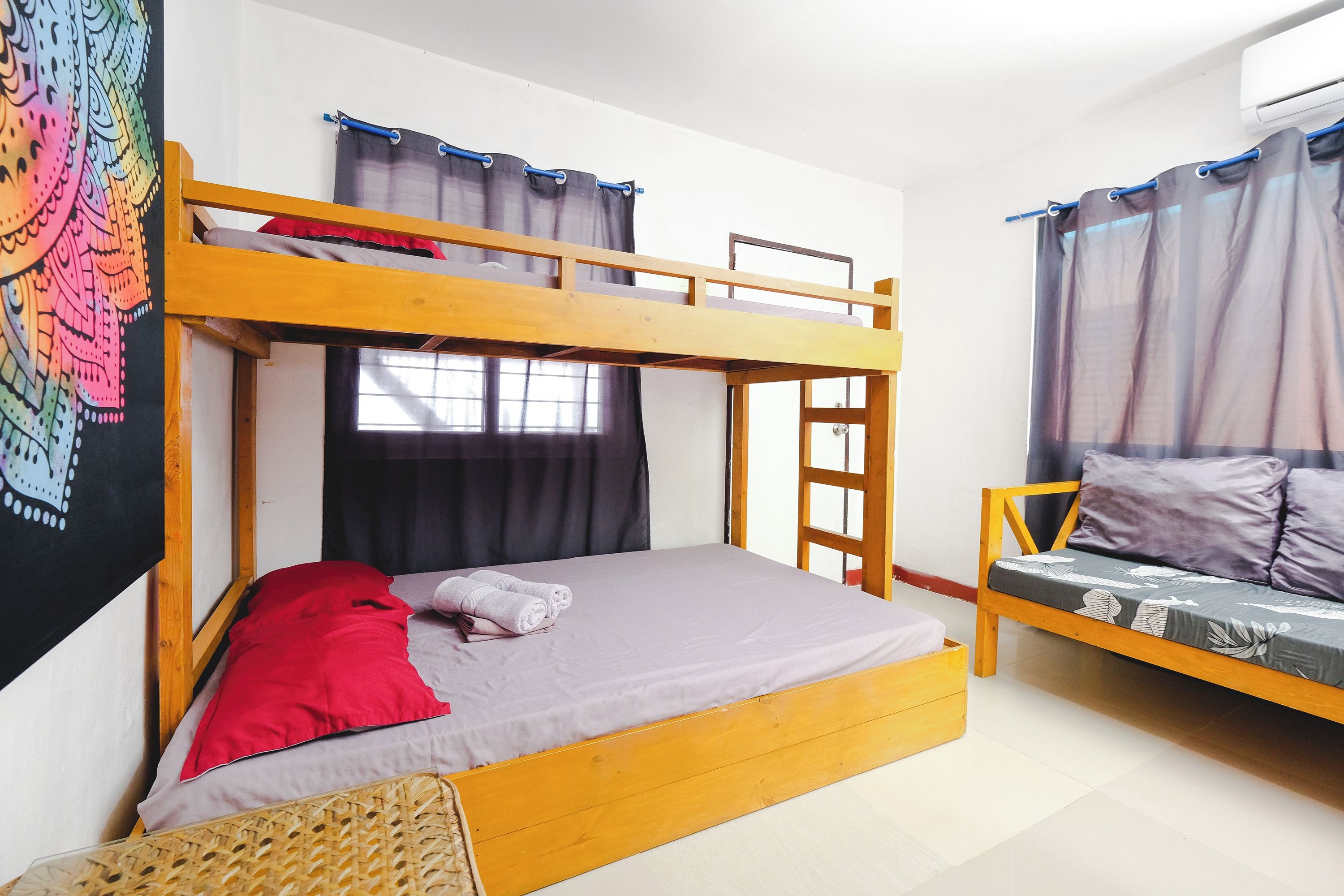 Uma beliche com escada, um sofá e uma janela com cortinas.