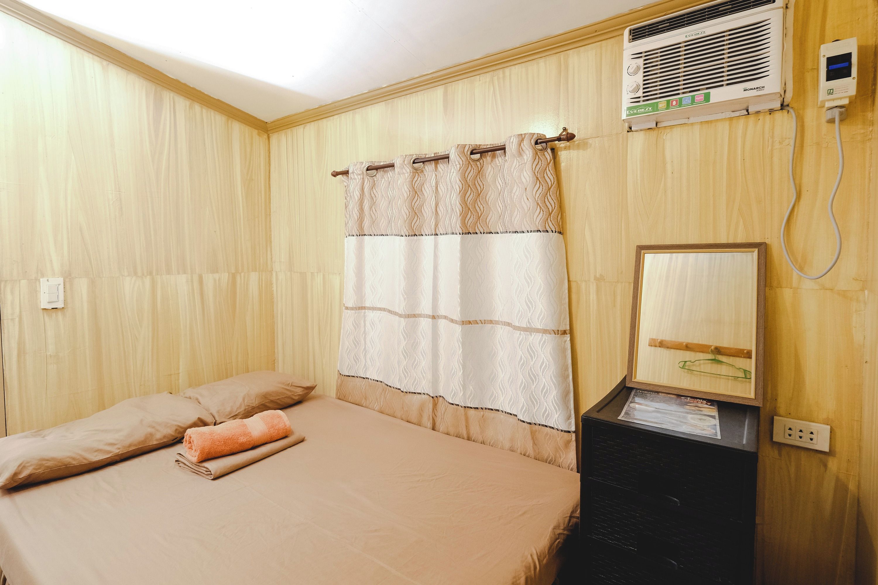 Quarto com uma cama, ar-condicionado fixado na parede e um espelho.