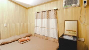 Quarto com uma cama, ar-condicionado fixado na parede e um espelho.