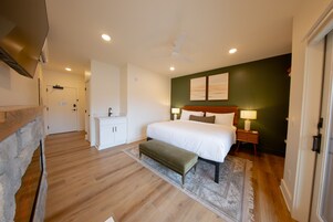 Quarto com cama, mesas de cabeceira, um banco, cômoda e ventilador de teto.