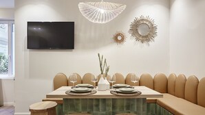 Uma sala de jantar moderna com uma mesa comprida, assentos de banco acolchoados e uma televisão na parede.