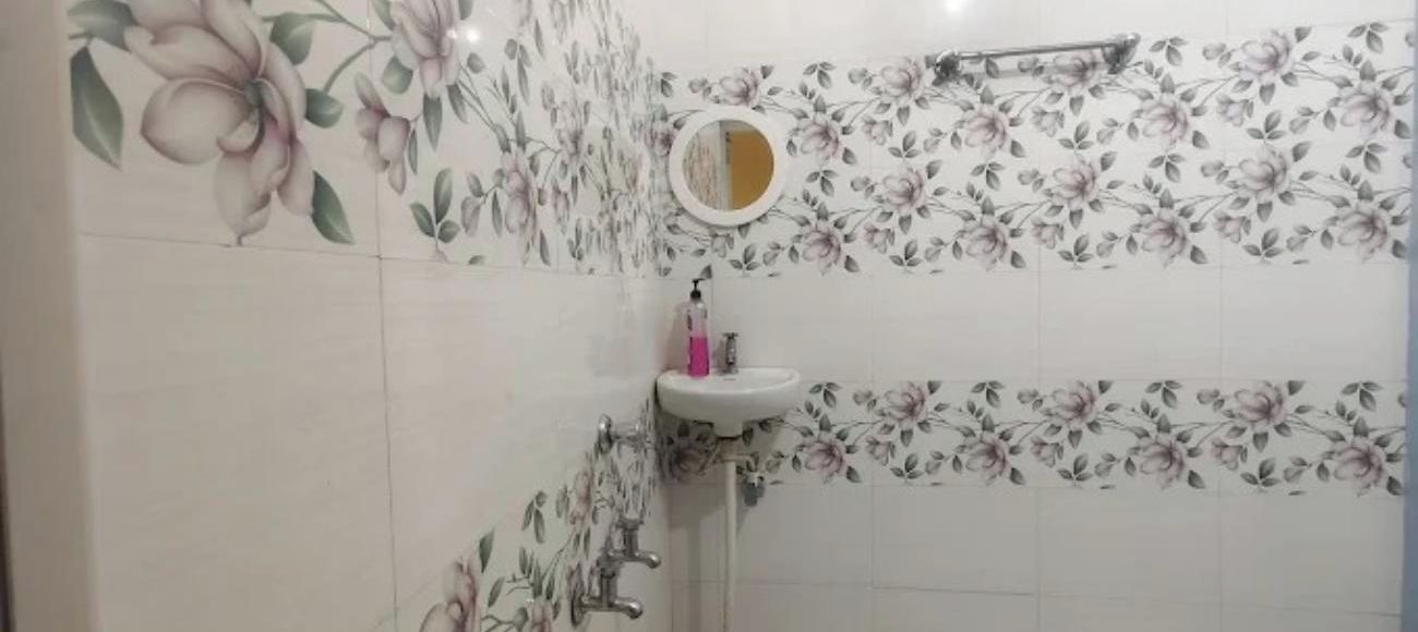 Um banheiro com papel de parede floral, pia com espelho e área de chuveiro.