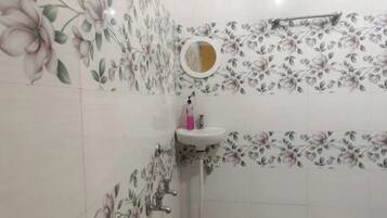 Um banheiro com papel de parede floral, pia com espelho e área de chuveiro.