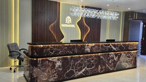 Um balcão de recepção de hotel com bancada de mármore, um candelabro e design moderno.