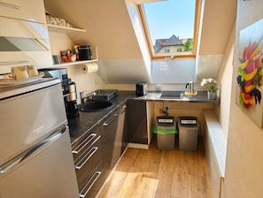 Uma cozinha compacta com forno embutido, pia e janela com vista para uma área residencial.