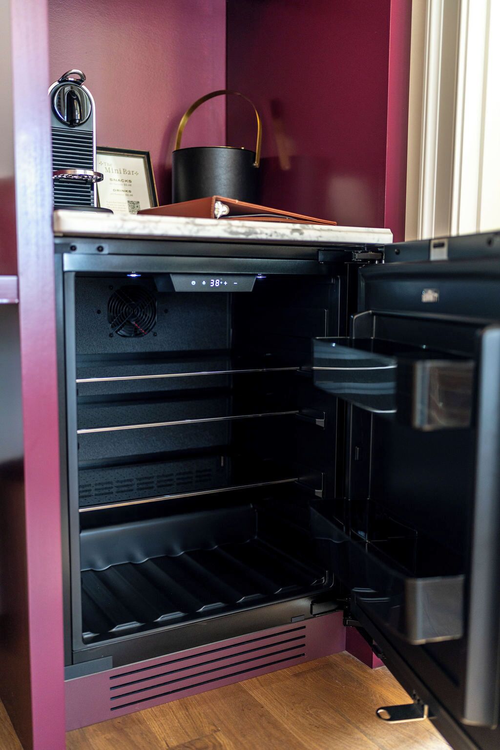 Uma cozinha compacta e moderna, com forno embutido e micro-ondas, um balcão pequeno e uma janela.
