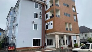 Um edifício residencial com várias andares, fachada cinzenta e parte superior marrom.