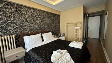 Quarto moderno com parede de mármore, colcha preta, mesa de cabeceira de madeira e guarda-roupa.