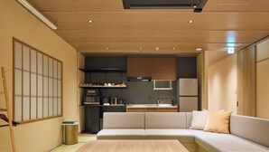Uma sala de estar moderna com um sofá, uma mesa de centro de madeira e uma área de cozinha com eletrodomésticos.