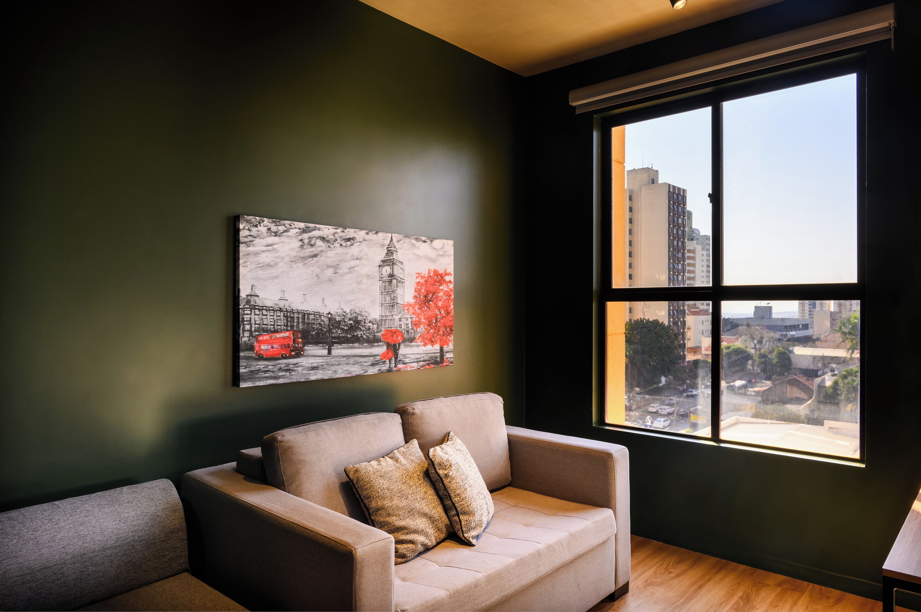 Uma sala de estar moderna com uma janela grande, um sofá bege e vista para a cidade.