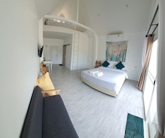 Um quarto espaçoso com uma cama grande, um espaço de estar com um sofá e poltronas, um quadro na parede e vista para o exterior.