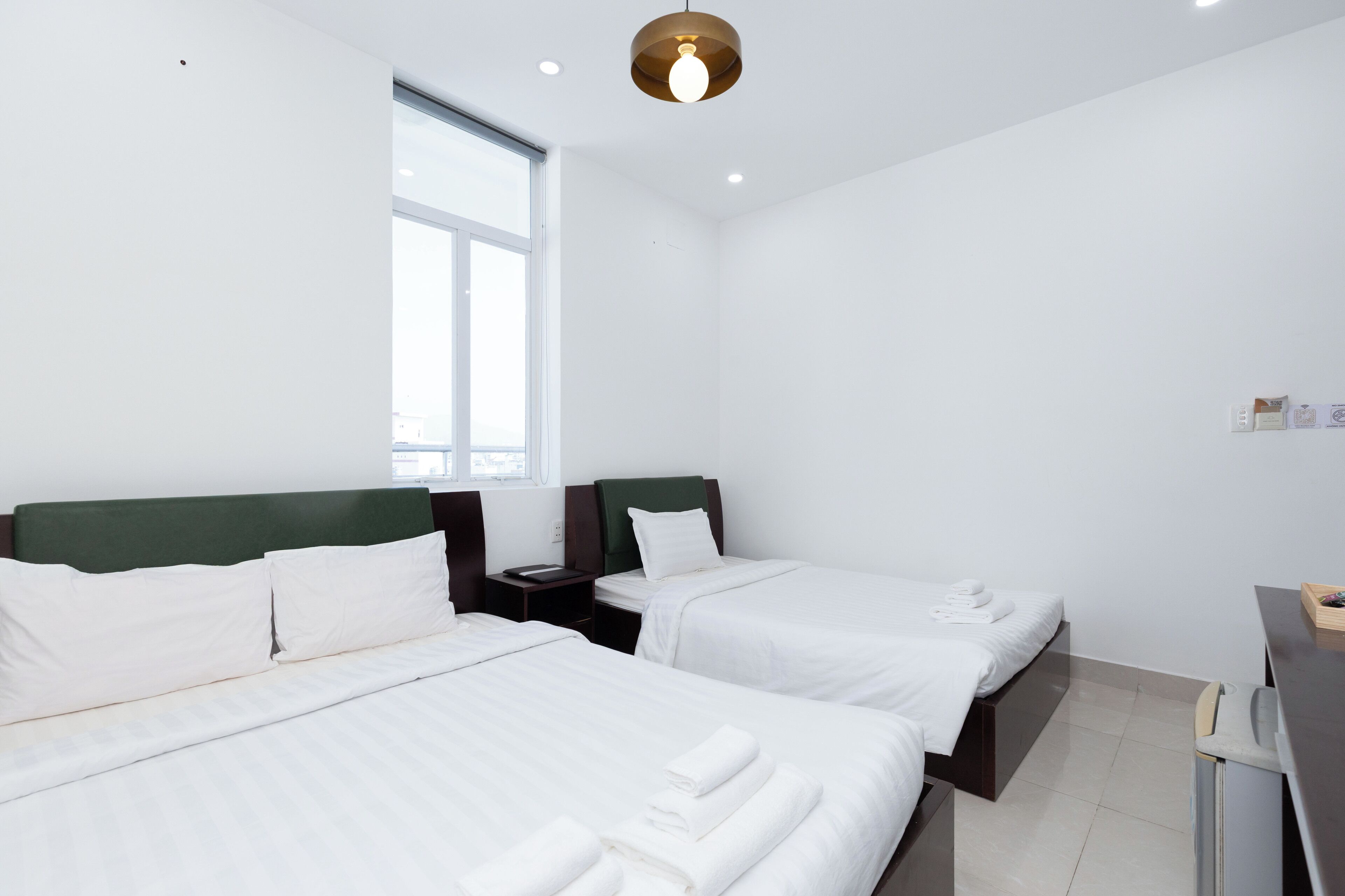 Quarto de hotel com duas camas, uma mesa e uma janela.