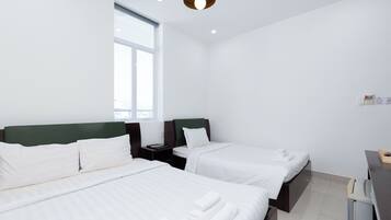 Quarto de hotel com duas camas, uma mesa e uma janela.