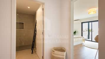 Quarto de hotel moderno com chuveiro, cama e vista para o exterior.