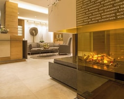 Uma sala de estar moderna com lareira de vidro, um sofá, uma mesa de centro e um painel decorativo.