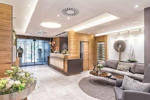 Uma área de recepção moderna com um balcão de madeira, um sofá cinzento e uma mesa de centro redonda.