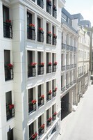 Um edifício com vários andares e varandas, cada uma decorada com flores vermelhas.