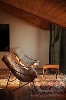 Um quarto com duas poltronas de couro, uma mesa de centro de madeira e um tapete estampado.
