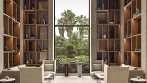 Uma sala de leitura moderna com grandes janelas, estantes e assentos confortáveis.