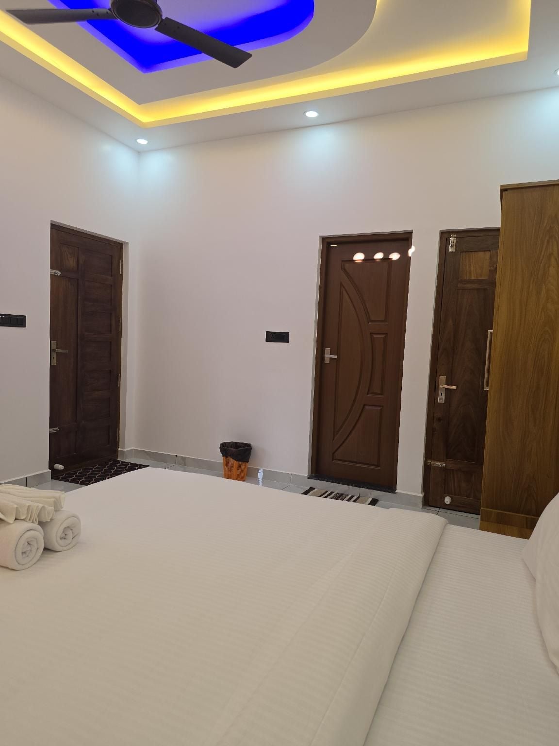 Quarto com cama, duas portas, ventilador de teto e iluminação embutida.