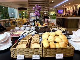 Buffet com diversos alimentos, incluindo pão, bolos e frutas.