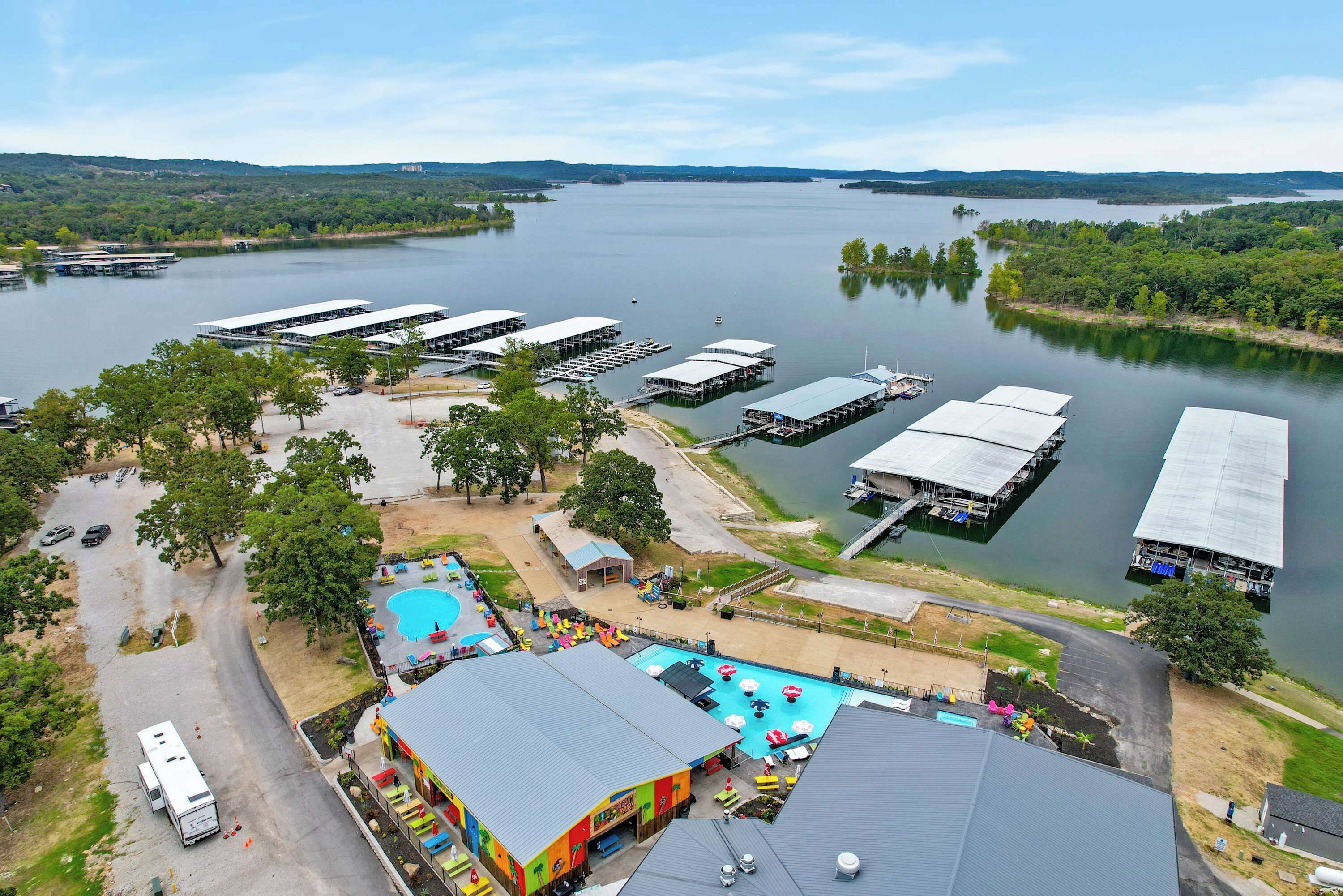 Uma propriedade à beira do lago com vários pontos de acesso para barcos, piscina e um edifício colorido.