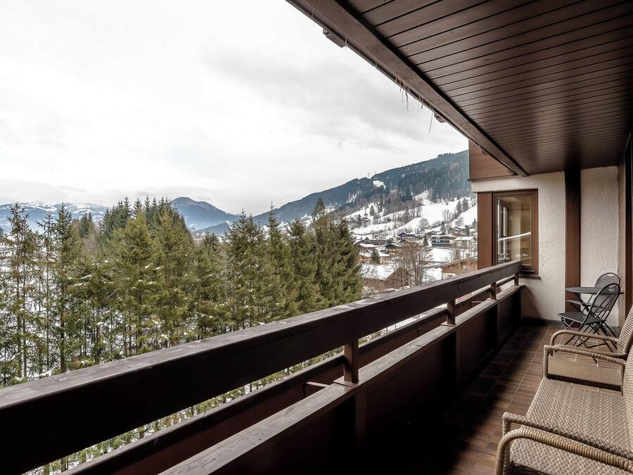 Varanda com vista para montanhas nevadas e árvores.