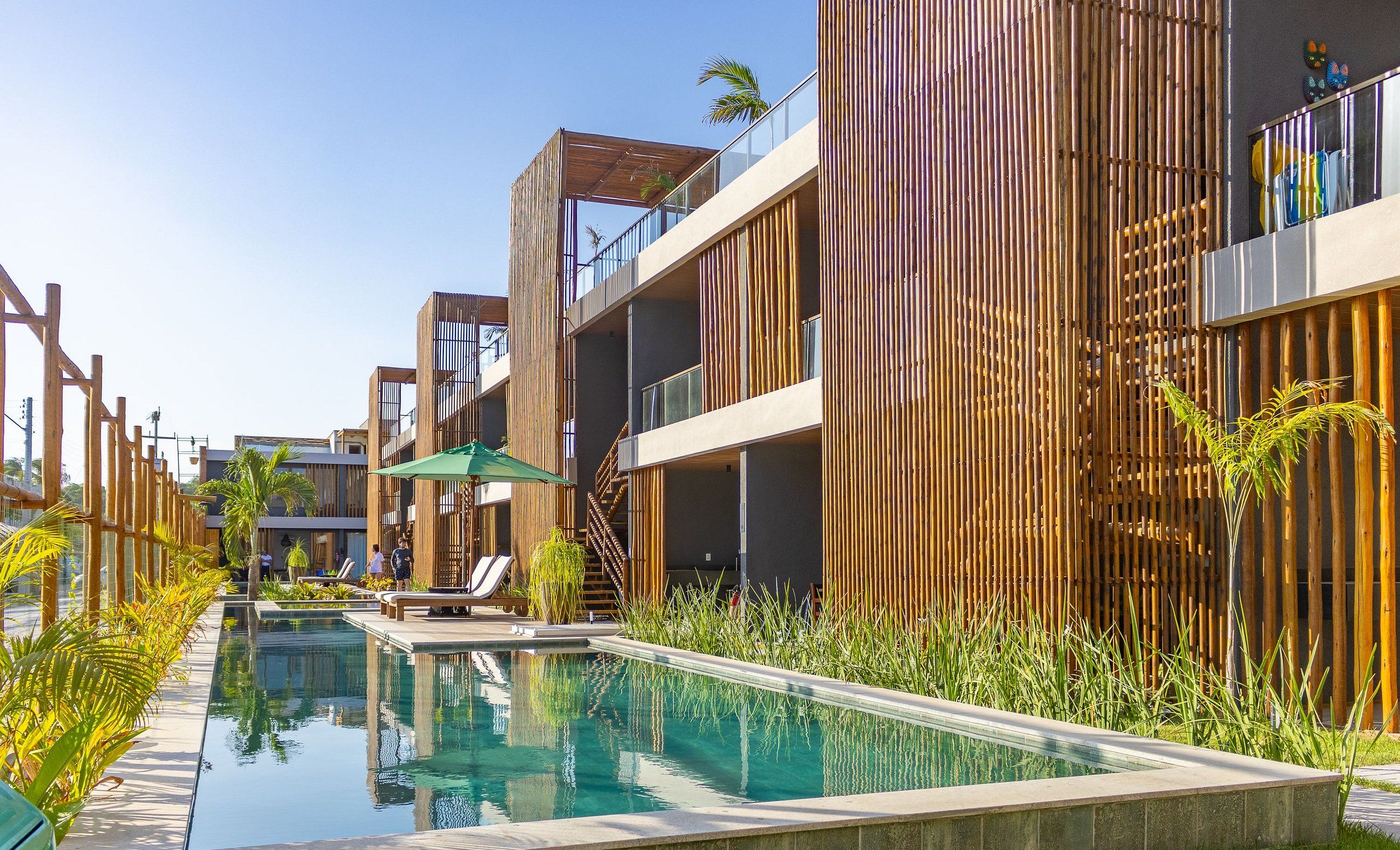 Um hotel moderno com piscina, paredes de ripas de madeira e área de estar ao ar livre.