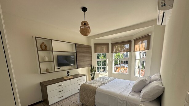 Quarto com cama, televisão, penteadeira e janela com vista para o exterior.