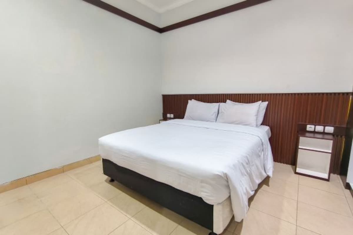 Quarto com cama, mesa de cabeceira e cabeceira de madeira.