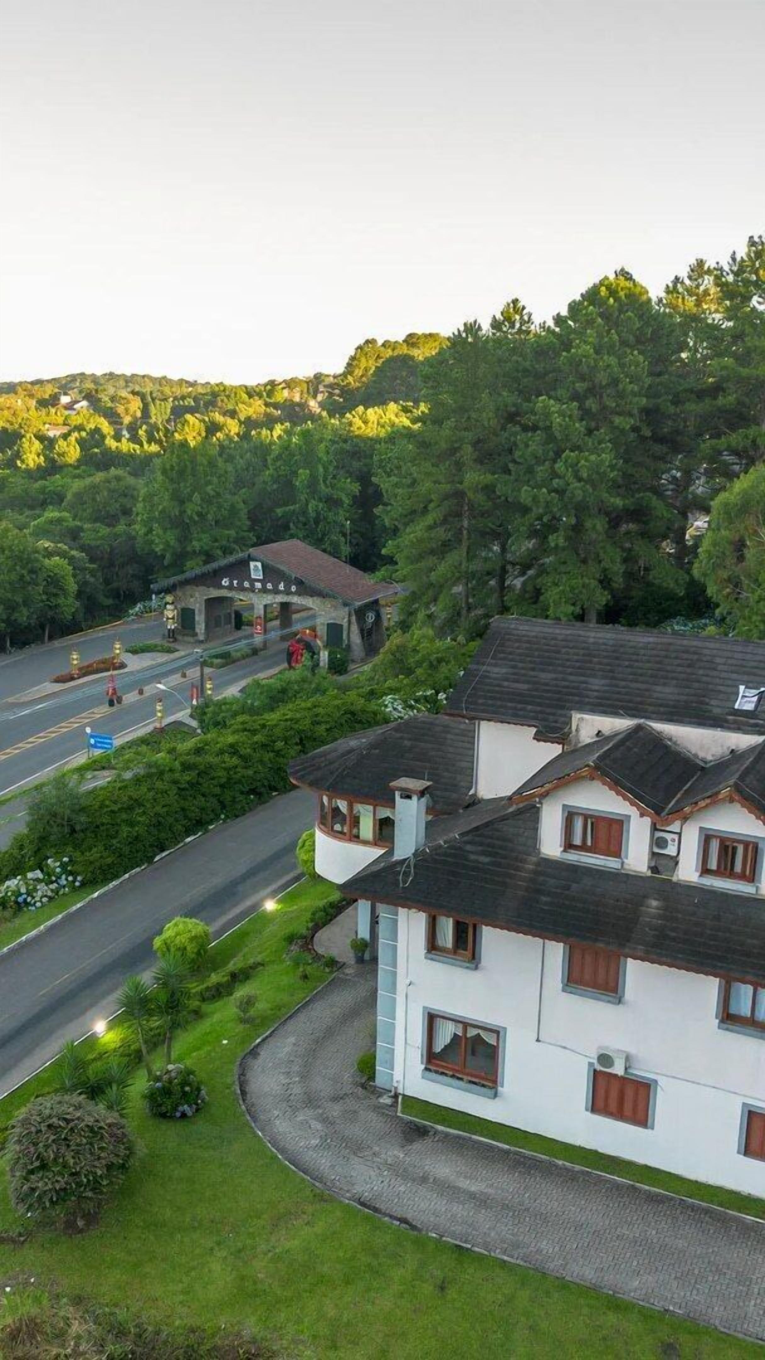 Um bairro residencial com casas, uma rua e um pequeno edifício com uma placa.