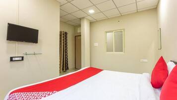 Quarto de hotel com cama, televisão na parede e janela.